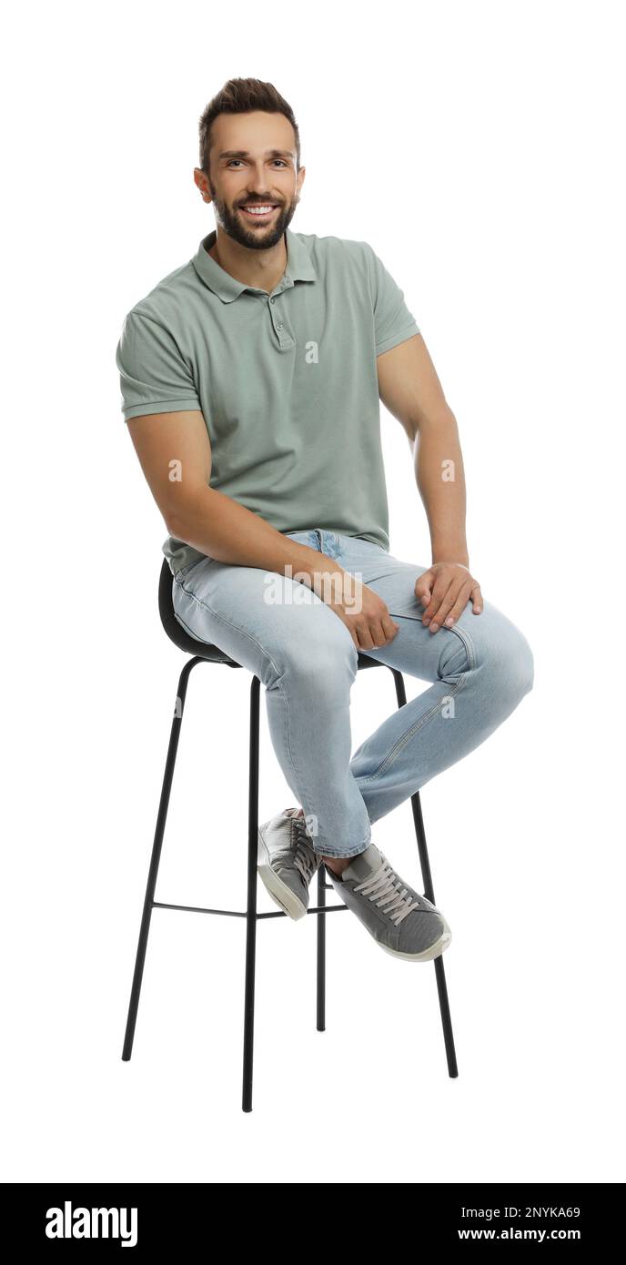 Handsome man sitting on stool against white background Stock Photo - Alamy