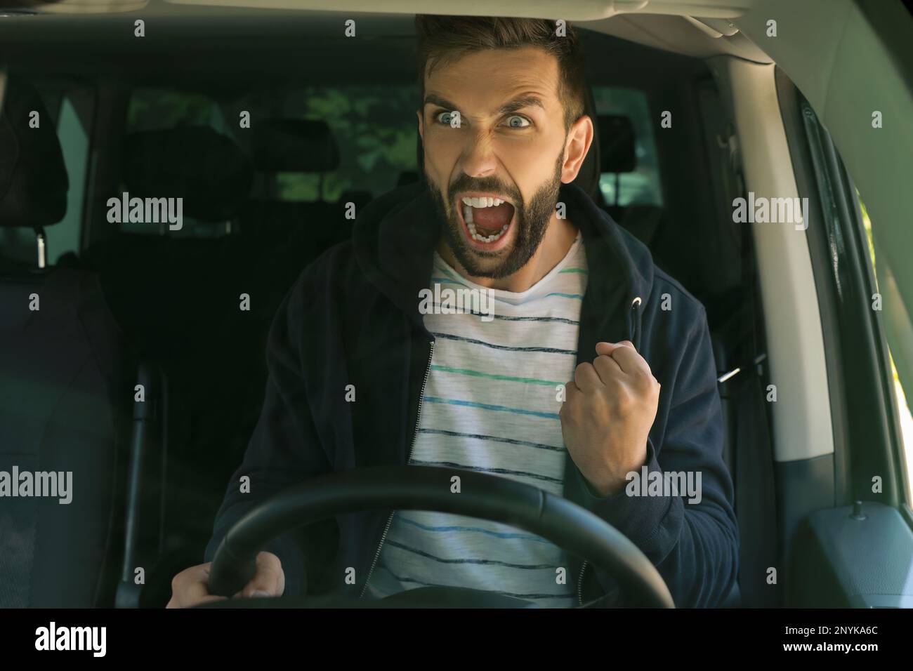 Stressed angry man in driver's seat of modern car, view through ...