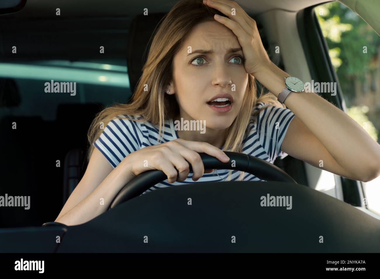 Stressed woman in driver's seat of modern car, view through windshield ...