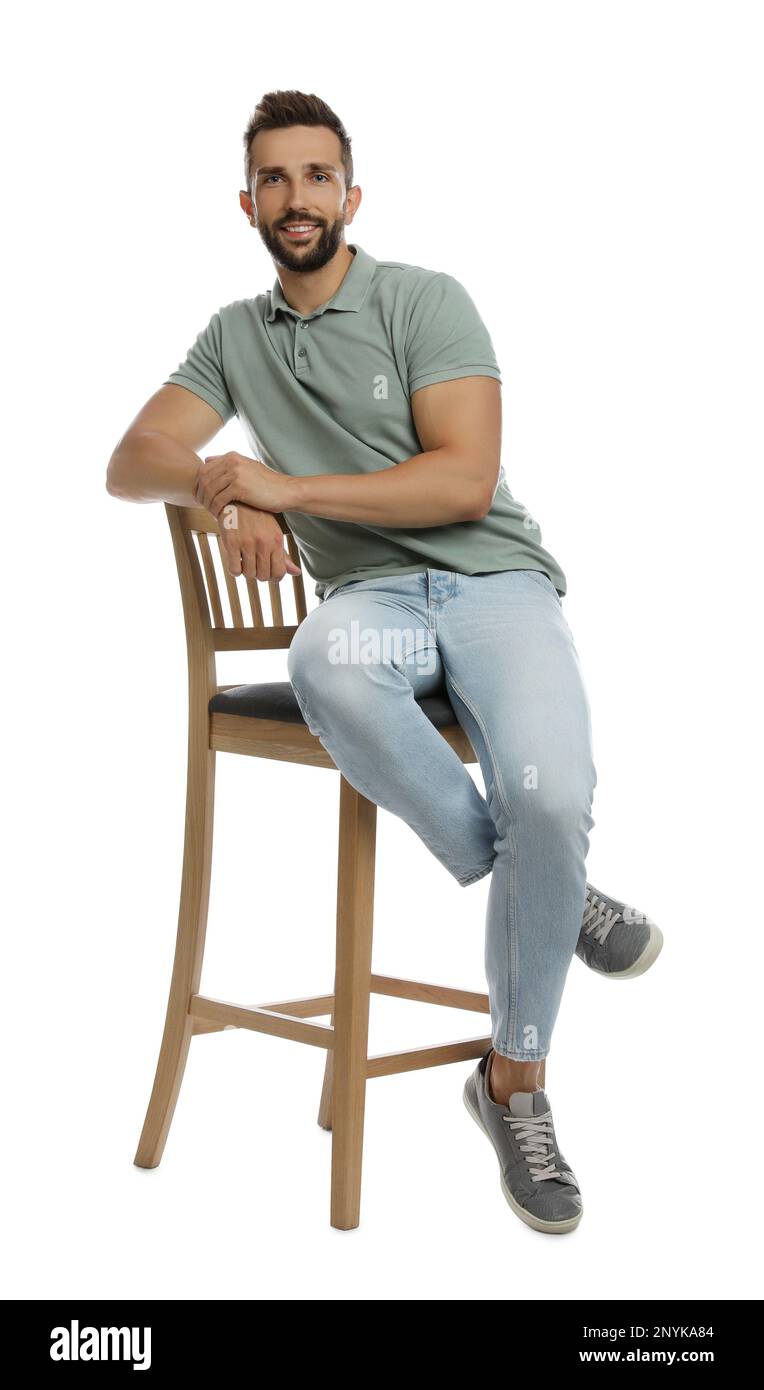 Handsome man sitting on stool against white background Stock Photo - Alamy