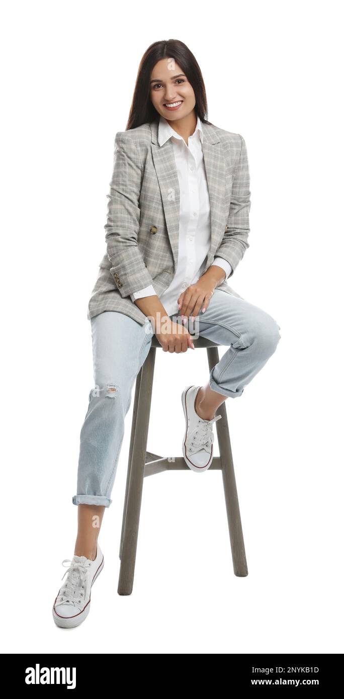 Beautiful young woman sitting on stool against white background Stock ...