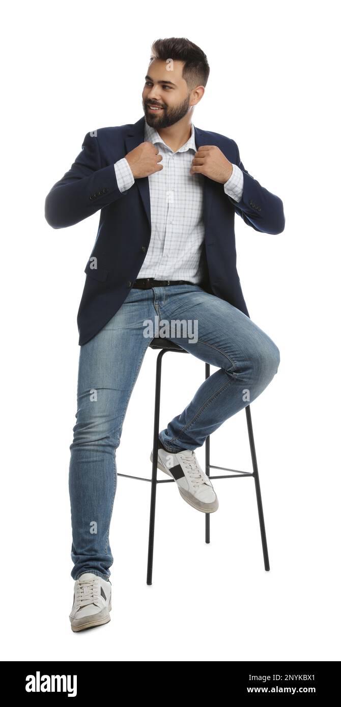 Handsome young man sitting on stool against white background Stock ...