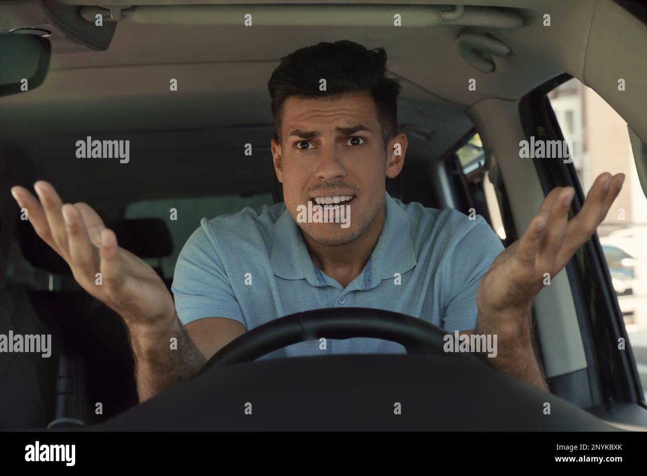 Stressed angry man in driver's seat of modern car, view through ...