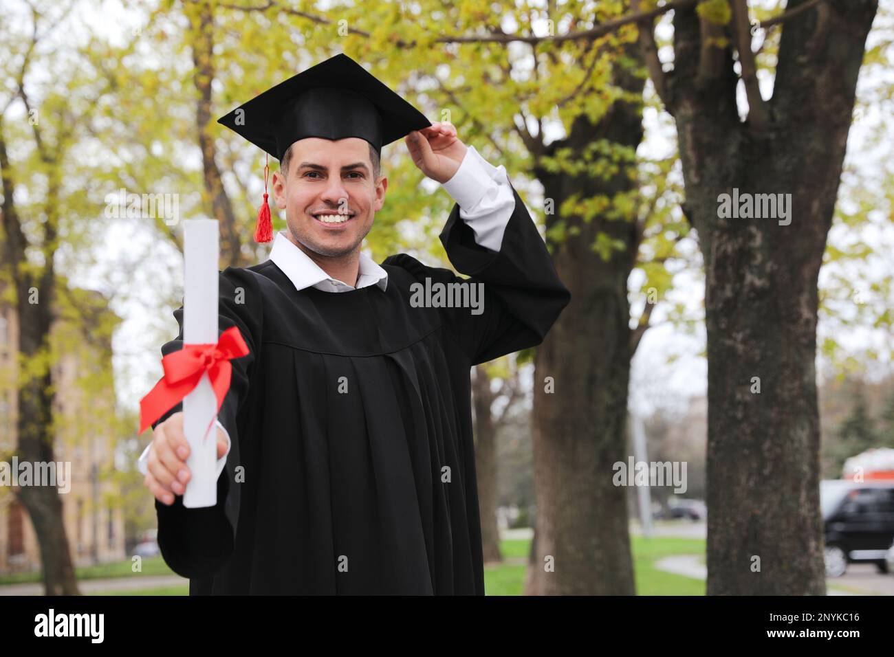 Happy student with diploma after graduation ceremony outdoors. Space ...