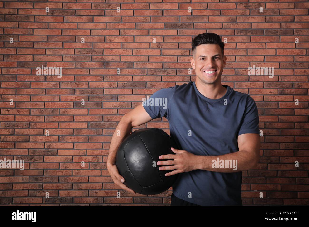 Athletic man with medicine ball near red brick wall Stock Photo - Alamy