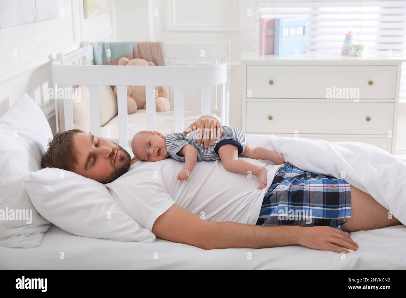 Tired young father sleeping with his baby in bed at home Stock Photo ...