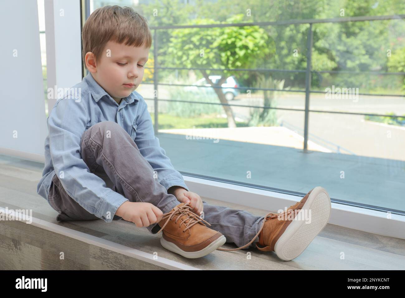 Cute little boy tying shoe laces at home, space for text Stock Photo ...