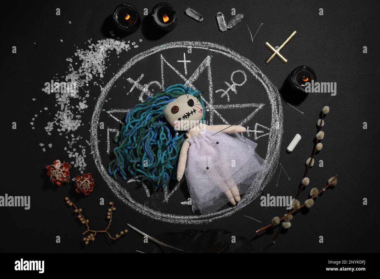 Female voodoo doll with pins surrounded by ceremonial items on black ...