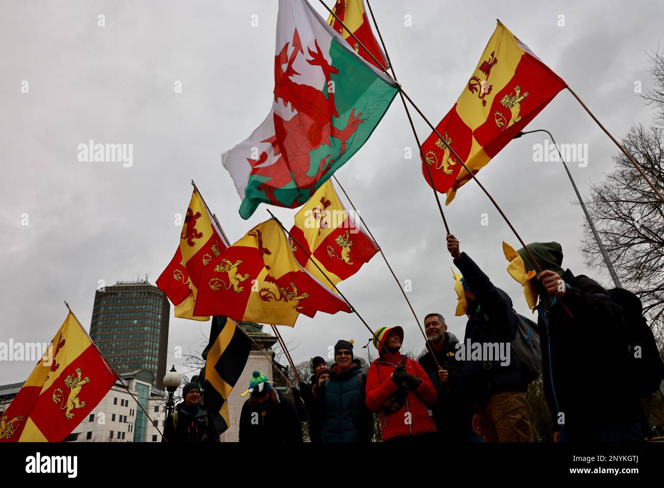 Parade participants march through the city center with Welsh flags ...