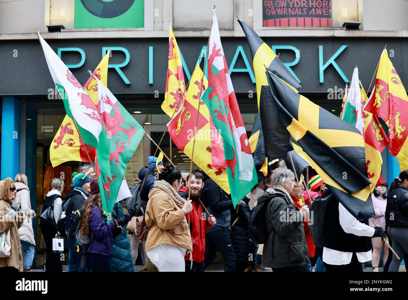 Parade participants march through the city center with Welsh flags ...