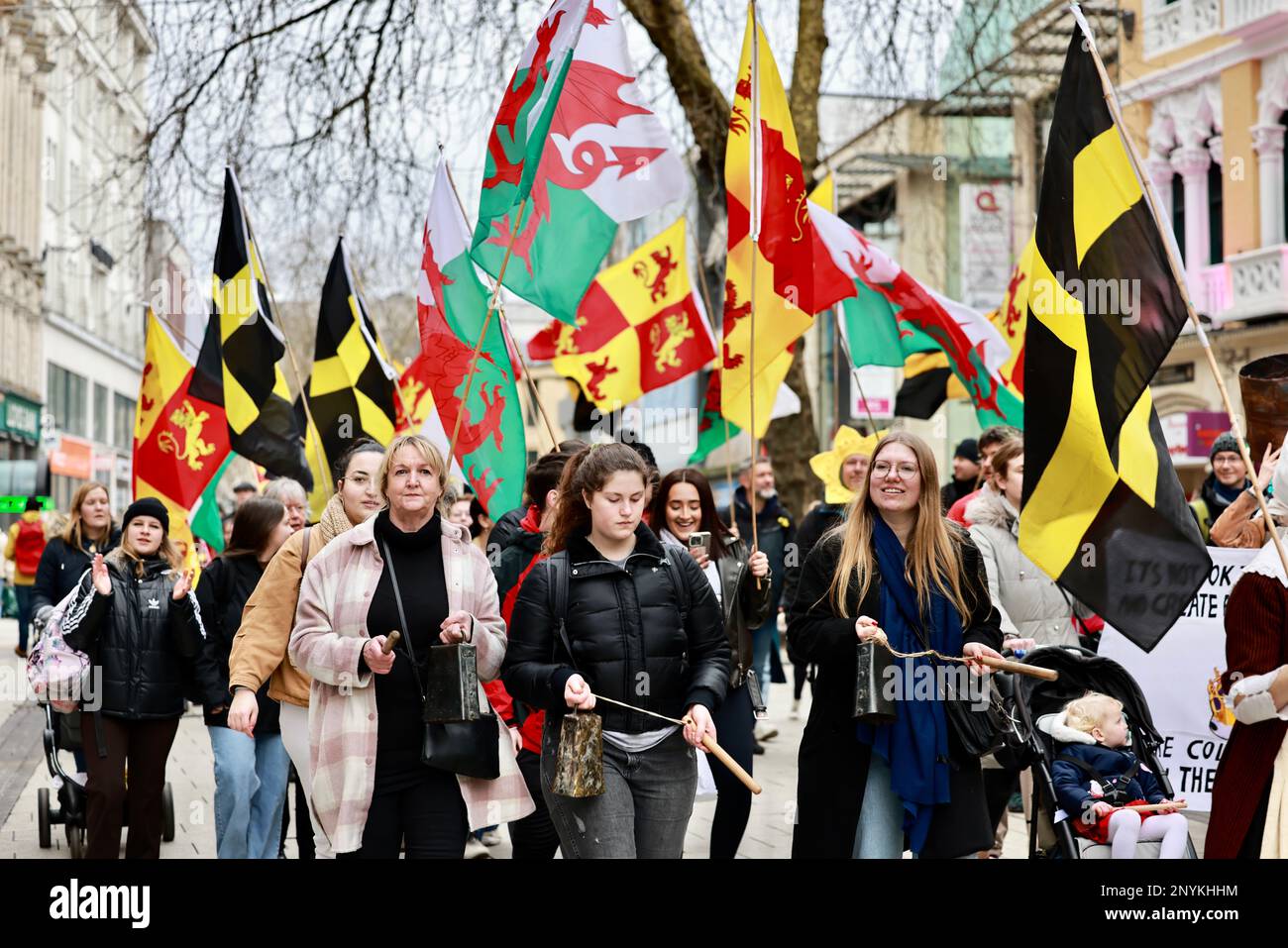 Parade participants march through the city center with Welsh flags ...
