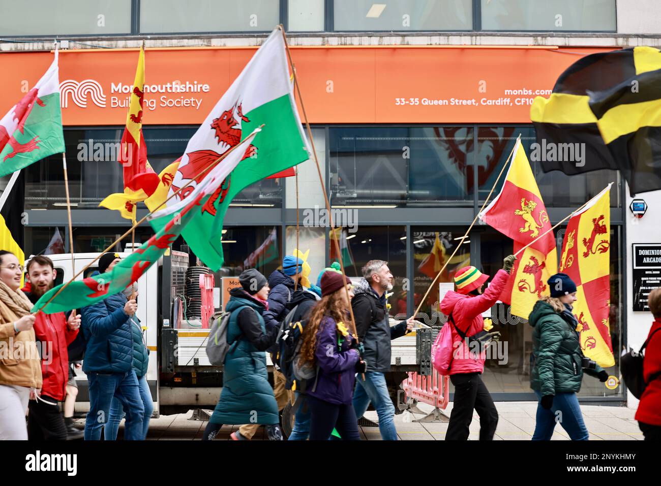 Parade participants march through the city center with Welsh flags ...