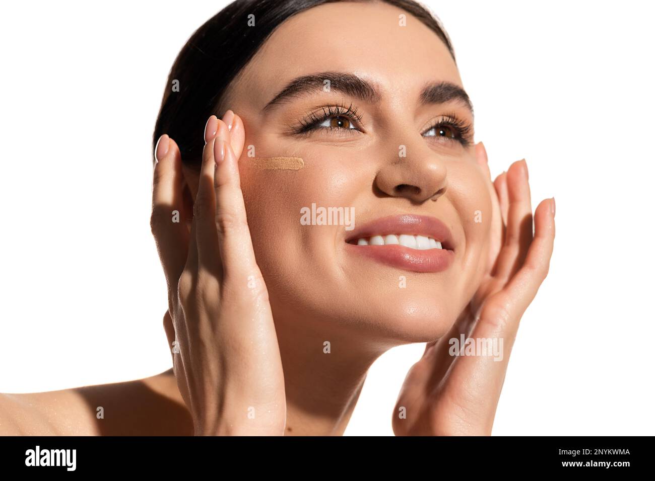 happy young woman with soft skin applying makeup foundation on cheek ...