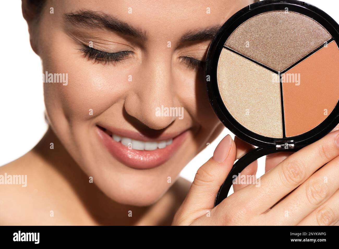close up view of happy young woman holding bronzer and highlighter ...