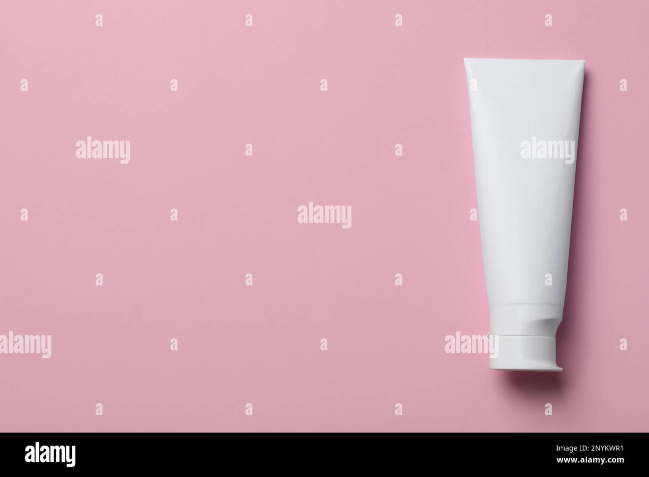 Blank tube of toothpaste on pink background, top view. Space for text ...