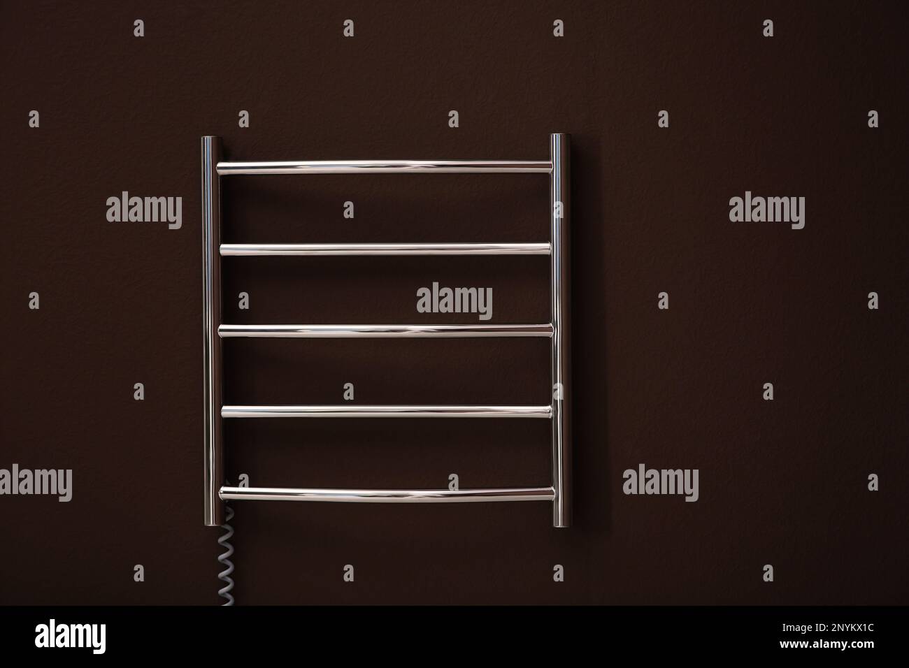 Modern heated towel rail on brown wall. Space for text Stock Photo - Alamy