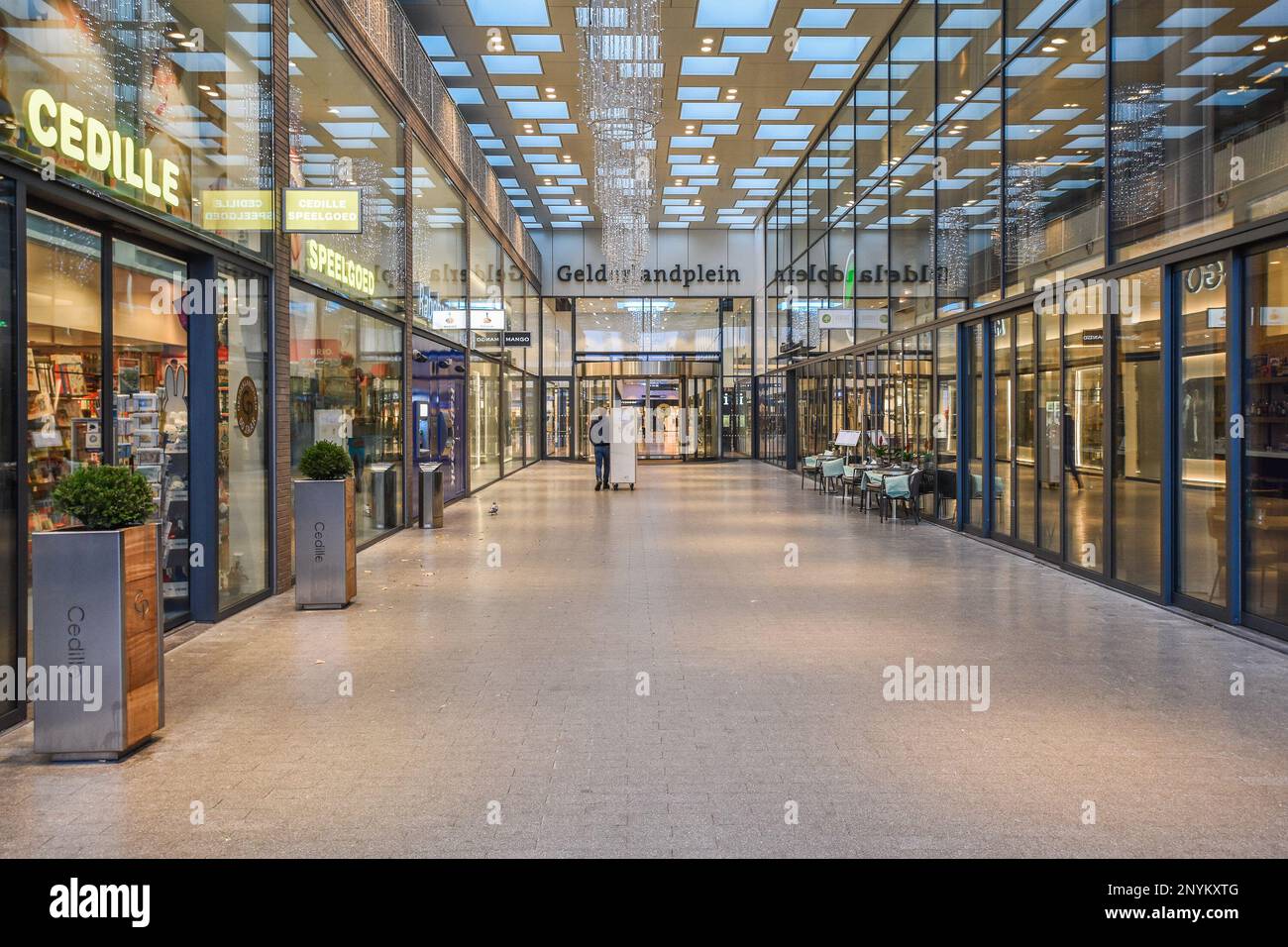an empty shopping mall with people walking down the hall and shops on ...