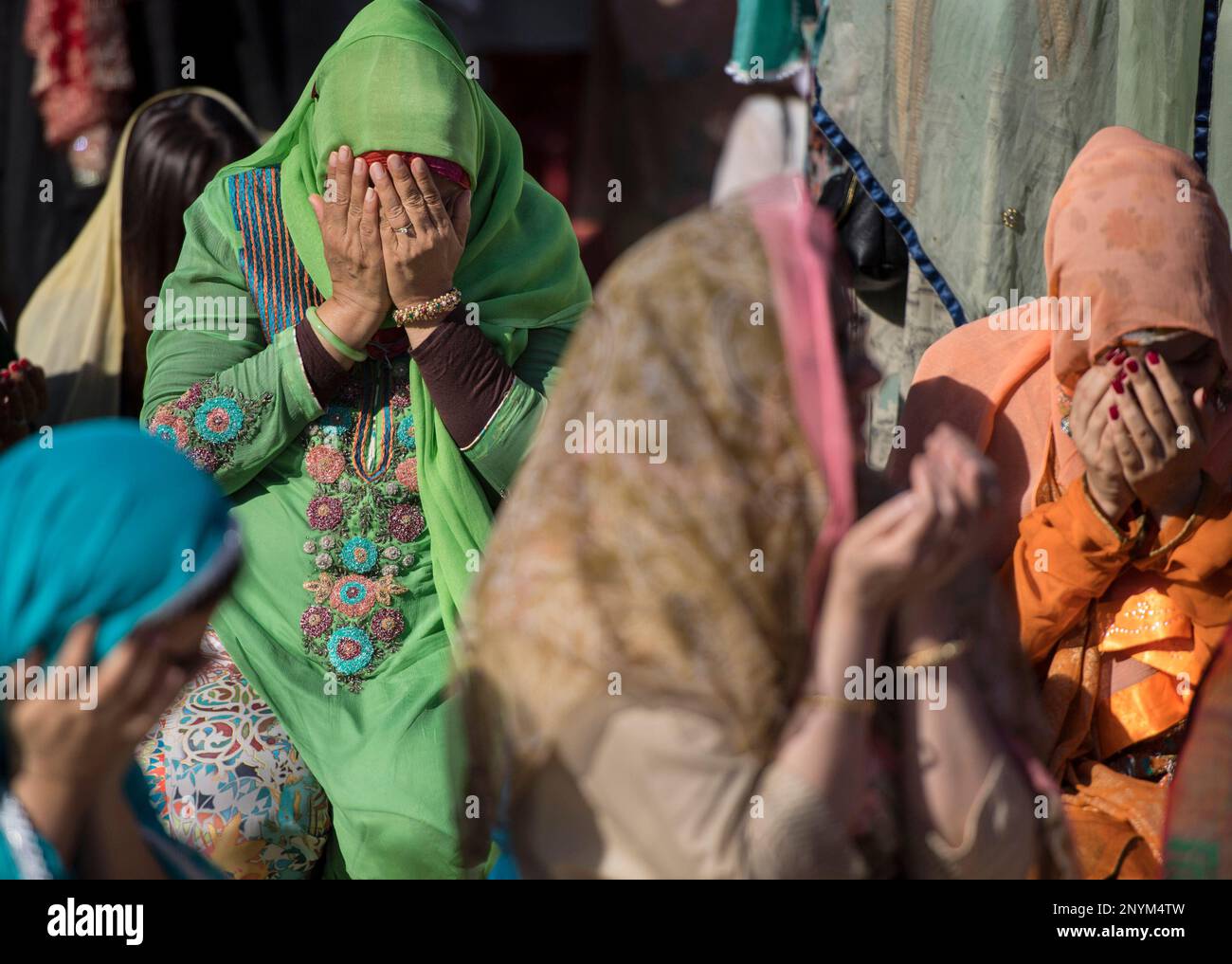 Women bow their heads in prayer as they attend a Eid al-Fitr ...