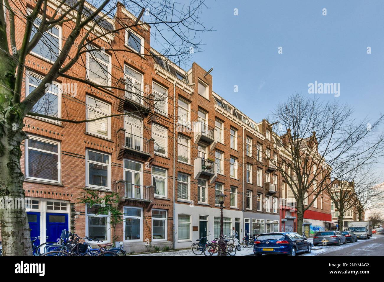 a city street with cars parked on the curbs and trees in front of some ...