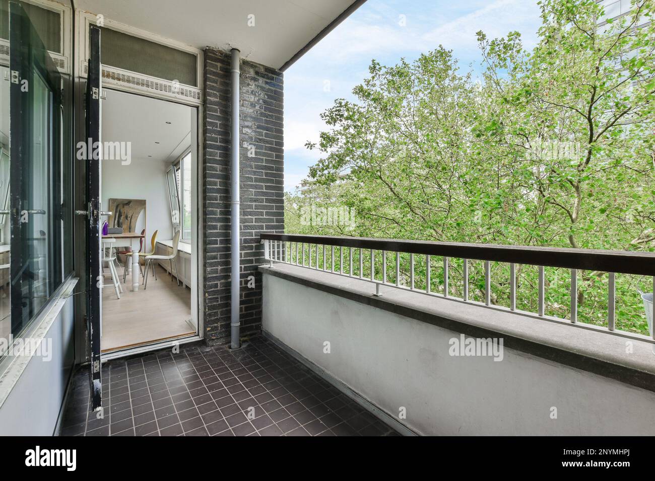 a balcony with trees in the background and an open door that leads to a ...