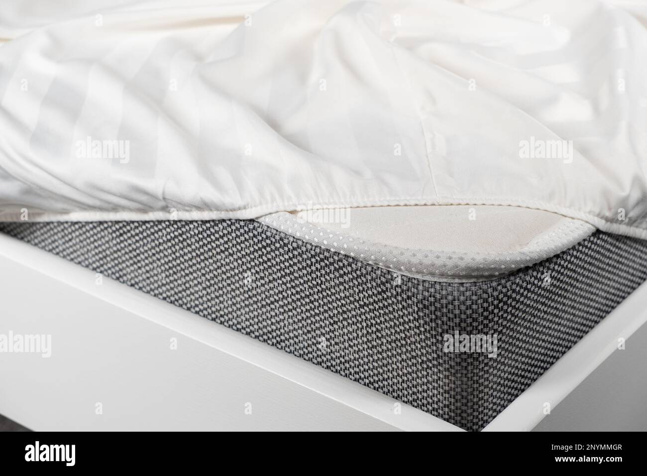 White satin sheet on an elastic band on the mattress. Bed linen on the ...