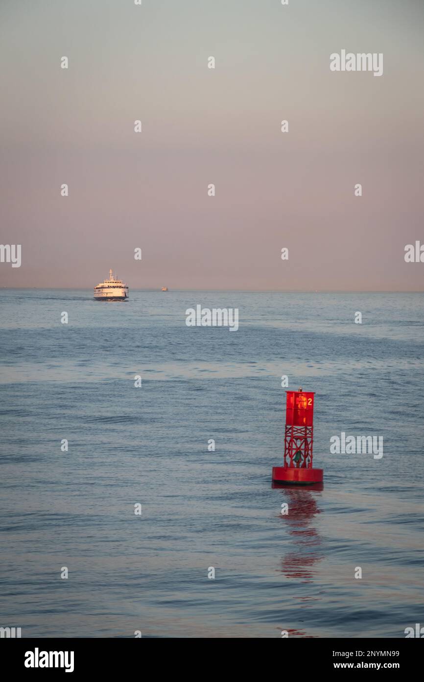 A bright red buoy in the middle of the ocean, with a small sailing ...