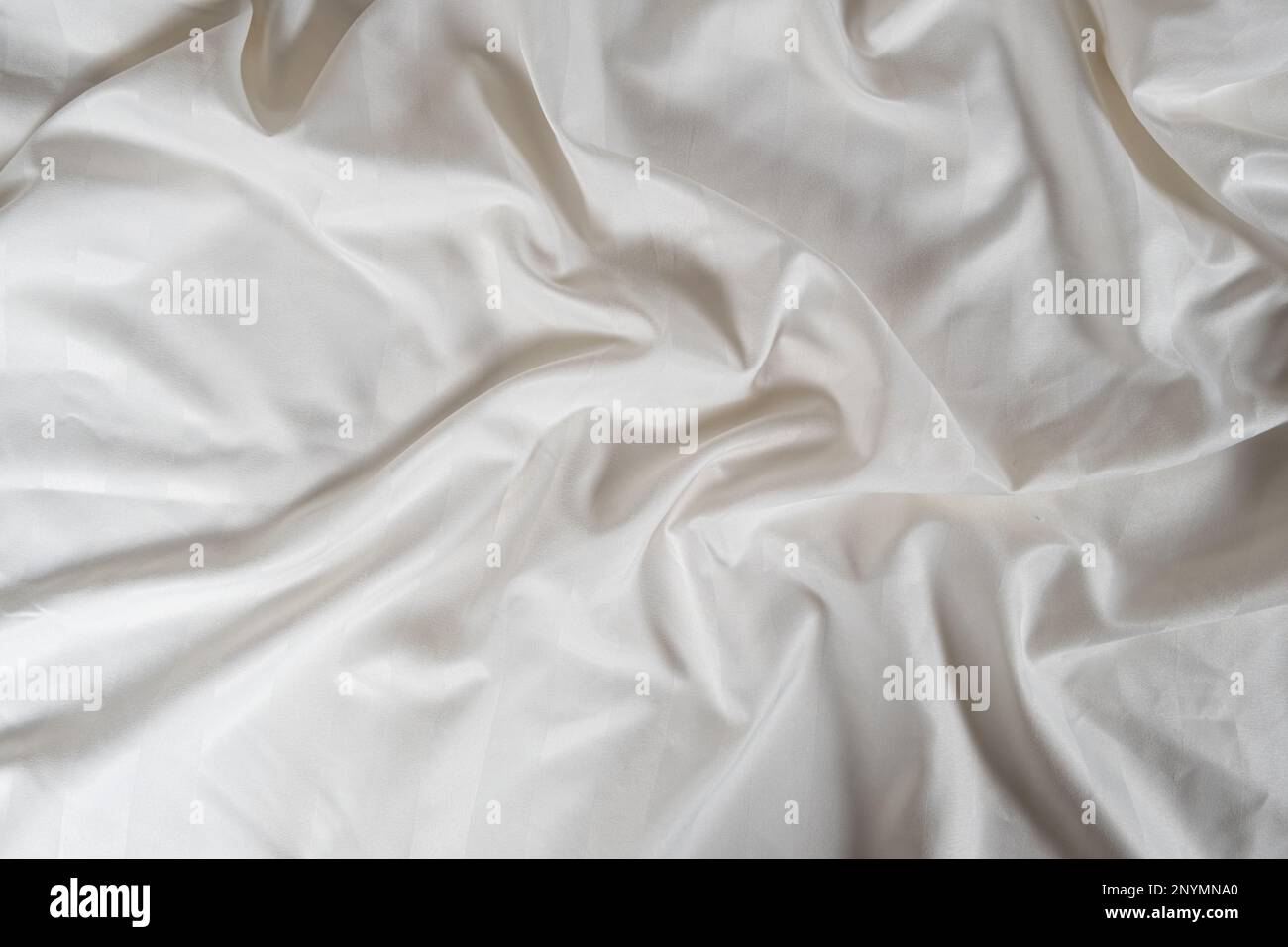 Satin crumpled fabric of light milky color, top view. Natural bed linen ...