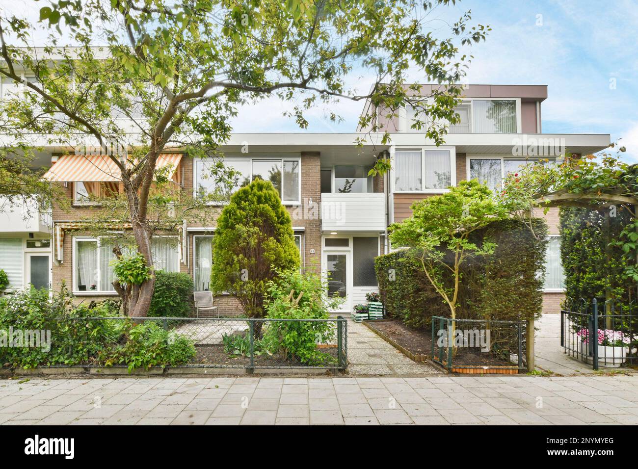 a house with trees in the front yard and bushes growing on the side of ...