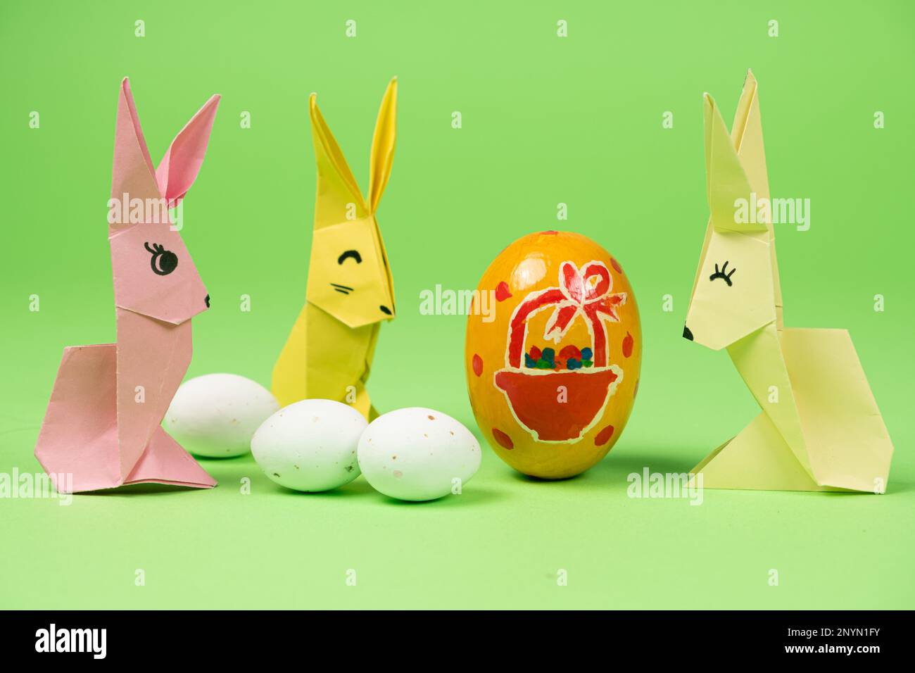 Easter origami - three paper bunnies and eggs, green background. Crafts ...