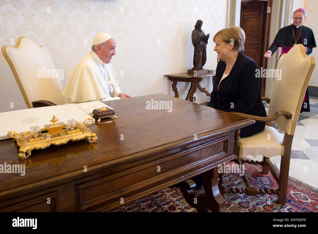 Pope Francis and German Chancellor Angela Merkel sit at a table on the ...