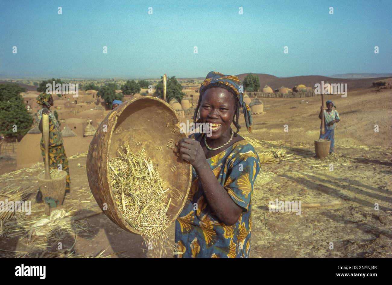 Niger, while women are pounding millet, another woman is winniwing the ...