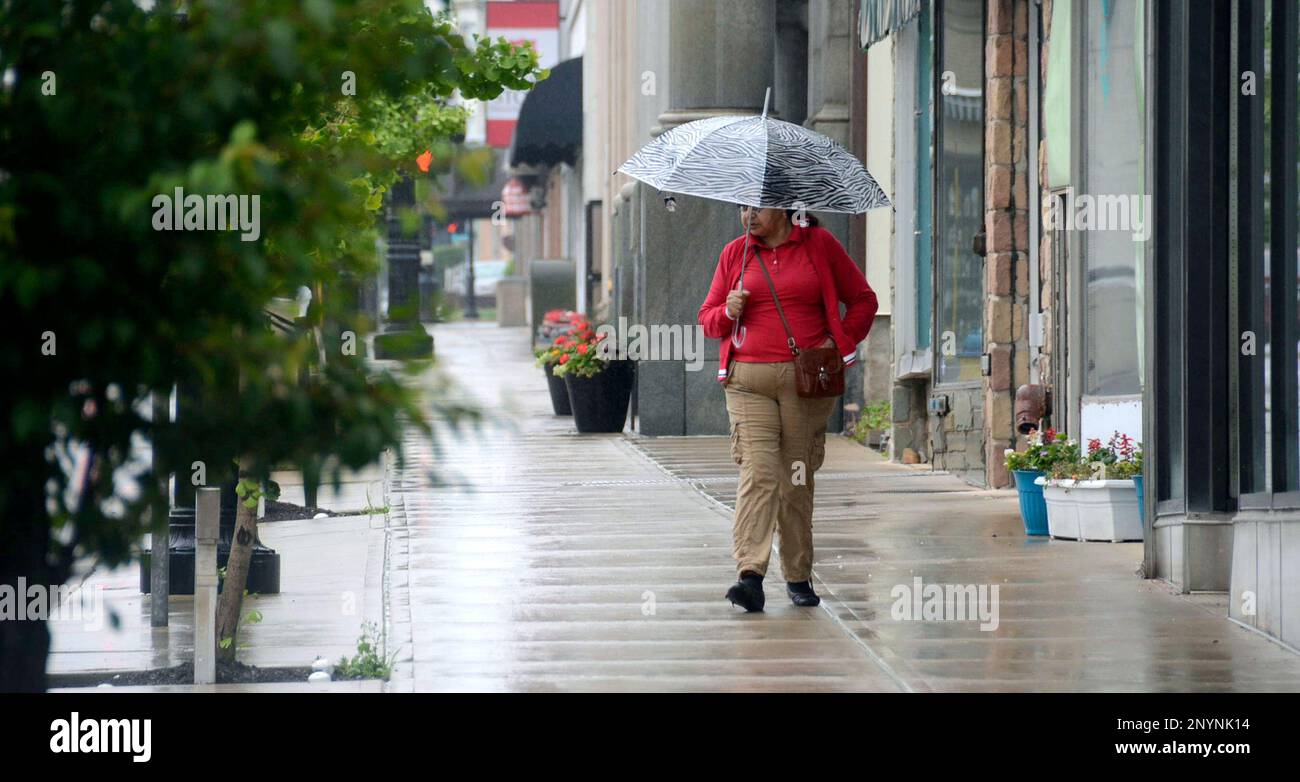 A women uses an umbrella to shield herself from the rain as she strolls ...