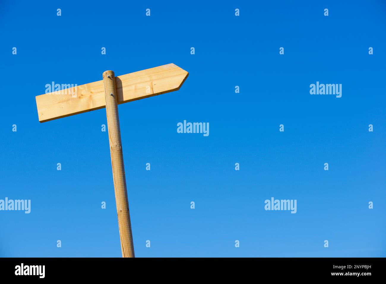 Wooden arrow on a pole indicating direction and clear blue sky Stock ...
