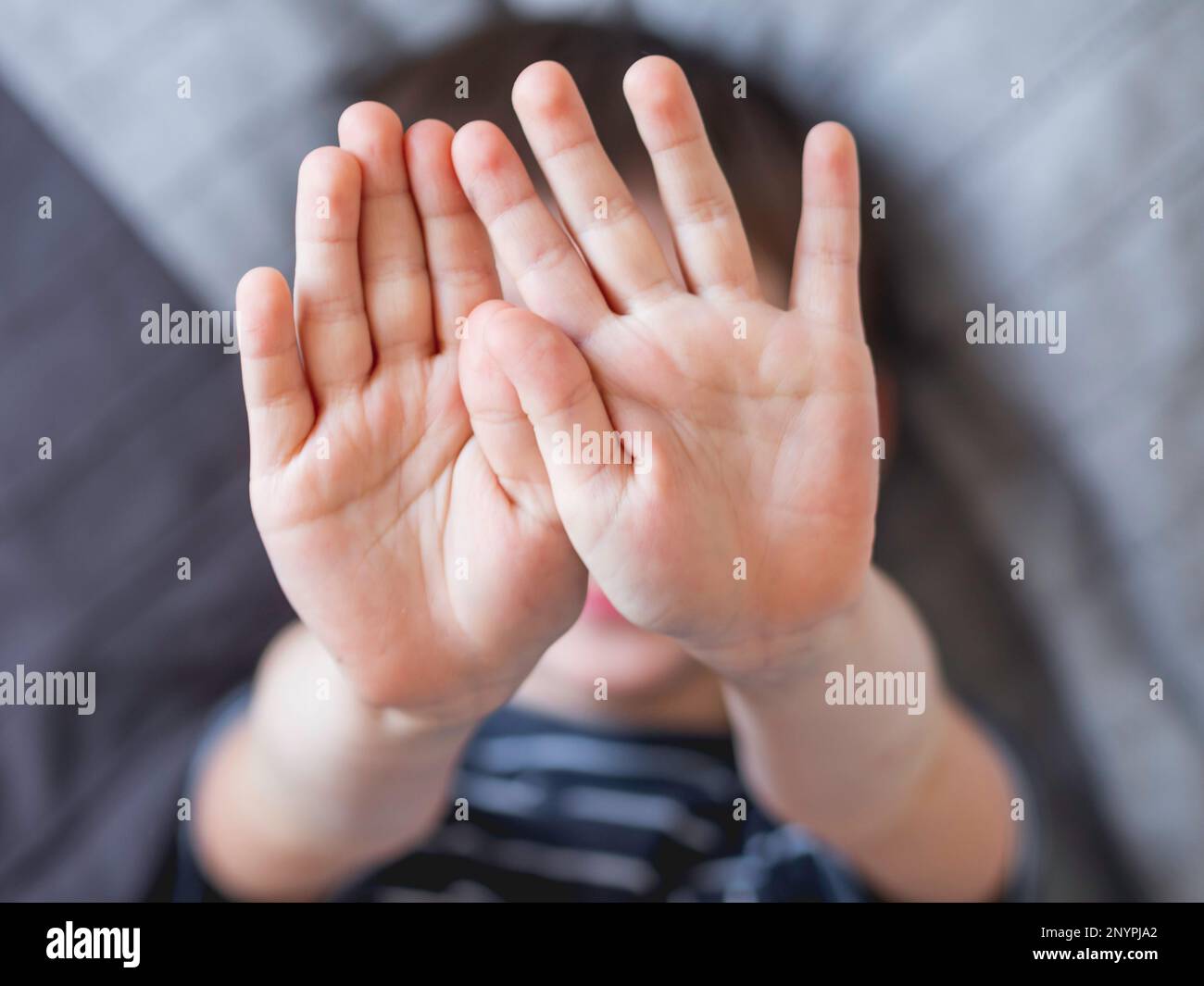 Little boy covers his face with hands. Child refuses to be photographed ...