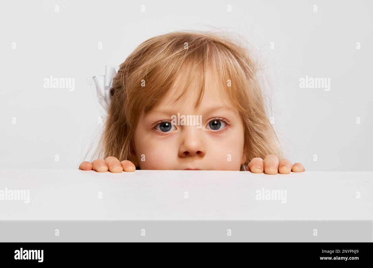 Curious kid. Cute little girl, child peeking out table, looking against ...