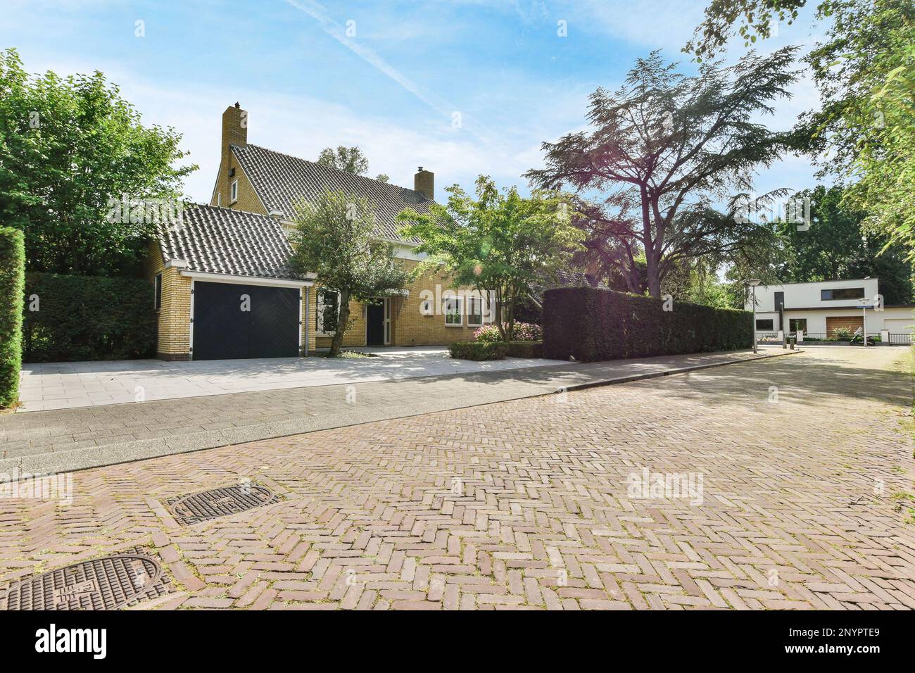 a brick driveway in front of a house with trees on both sides and a ...