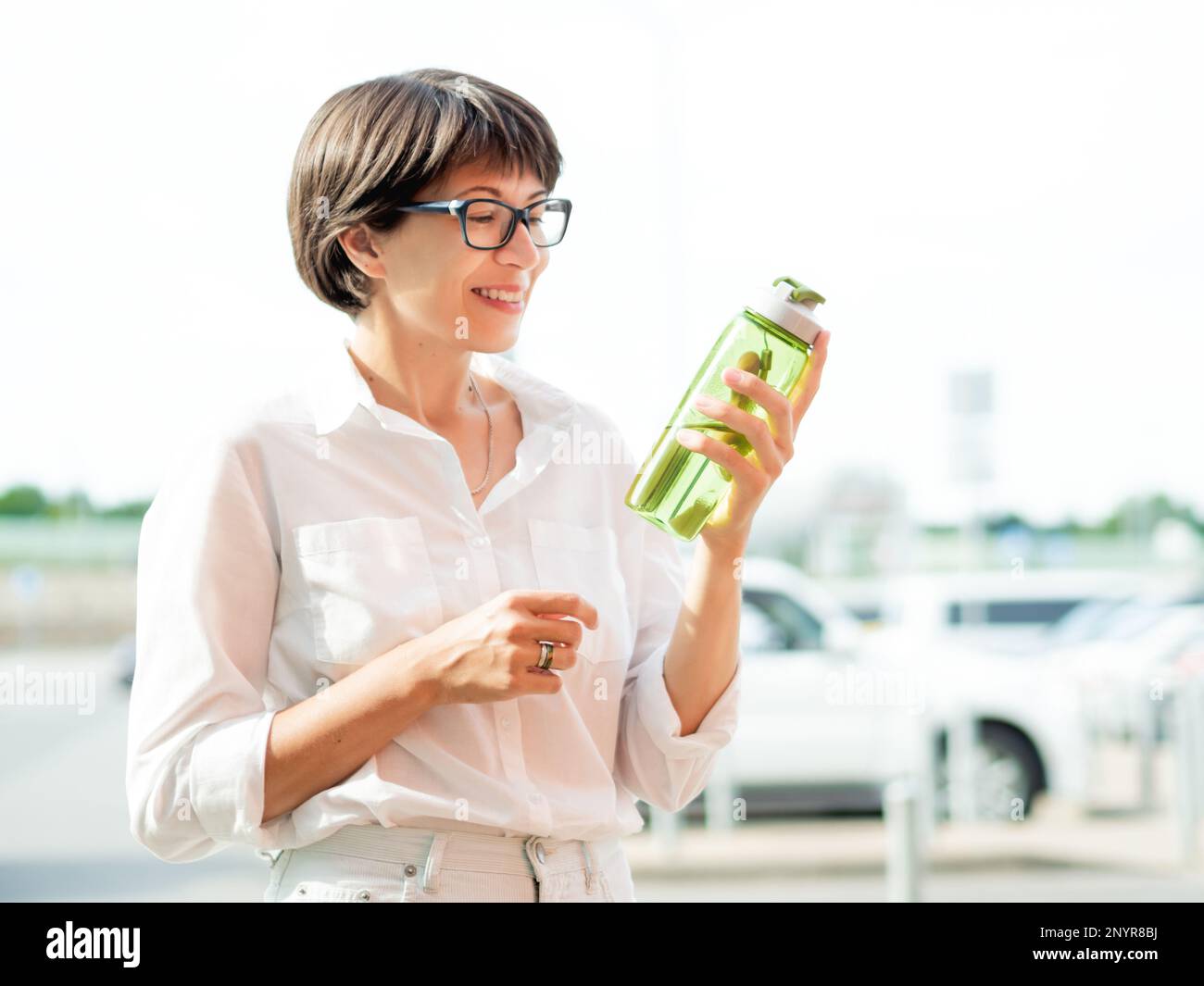 Thirsty woman drinks water from refilled green bottle. Useful ...