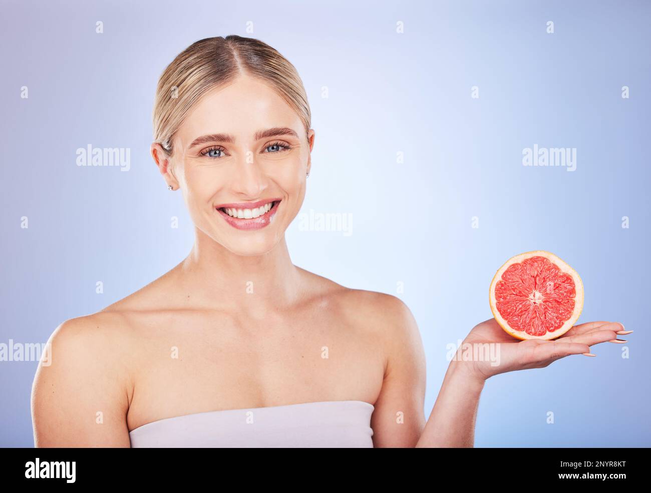 Skincare, face portrait and woman with grapefruit in studio isolated on a blue background. Food ...