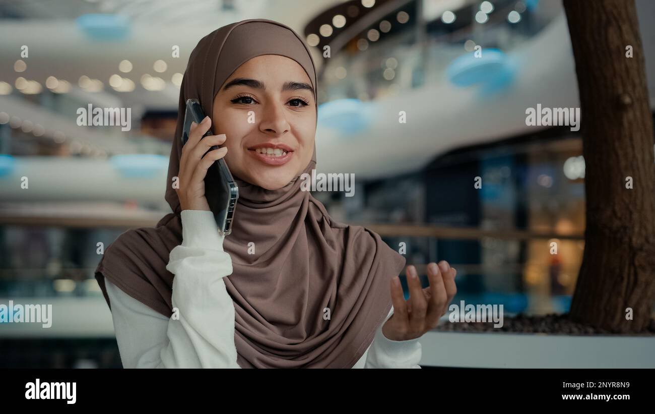 Beautiful muslim woman in hijab sitting in public place talk mobile ...