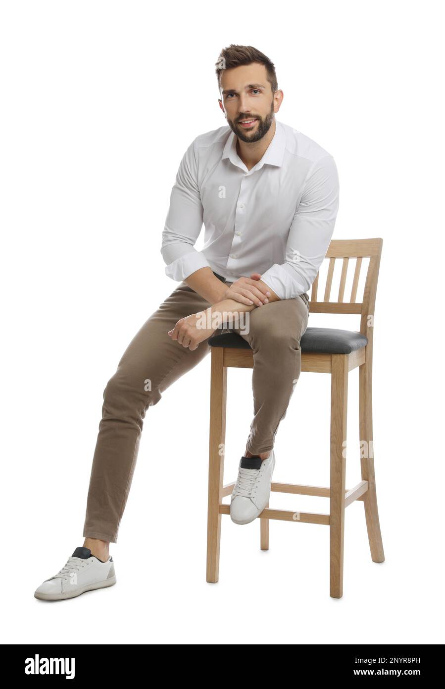 Handsome man sitting on stool against white background Stock Photo - Alamy