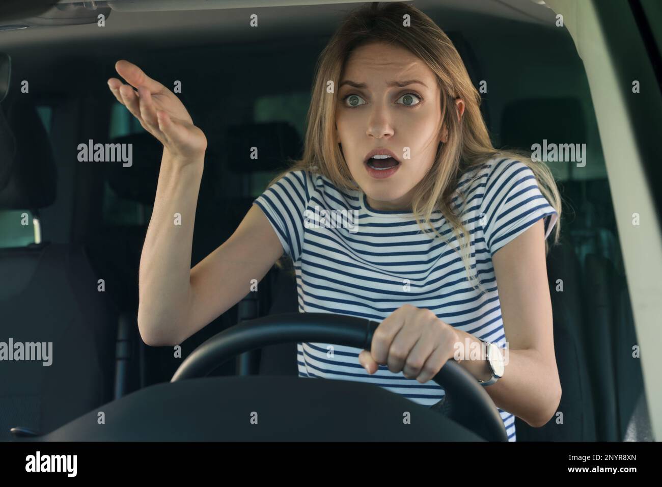 Stressed woman in driver's seat of modern car, view through windshield ...