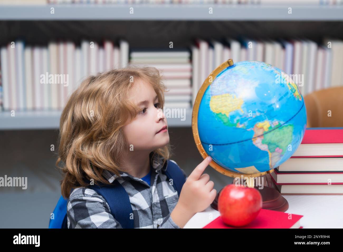 Pupil looking at globe in library at the elementary school. Nerd school ...