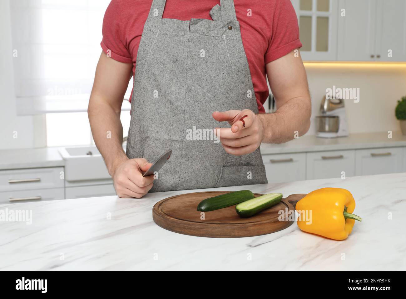 Man cut finger with knife while cooking at white marble table in ...