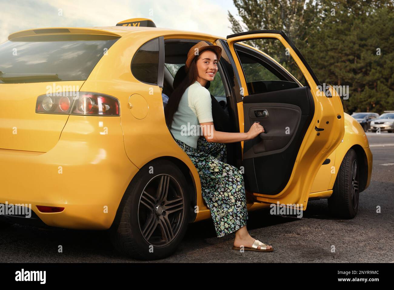 Beautiful young woman getting out of taxi on city street Stock Photo ...