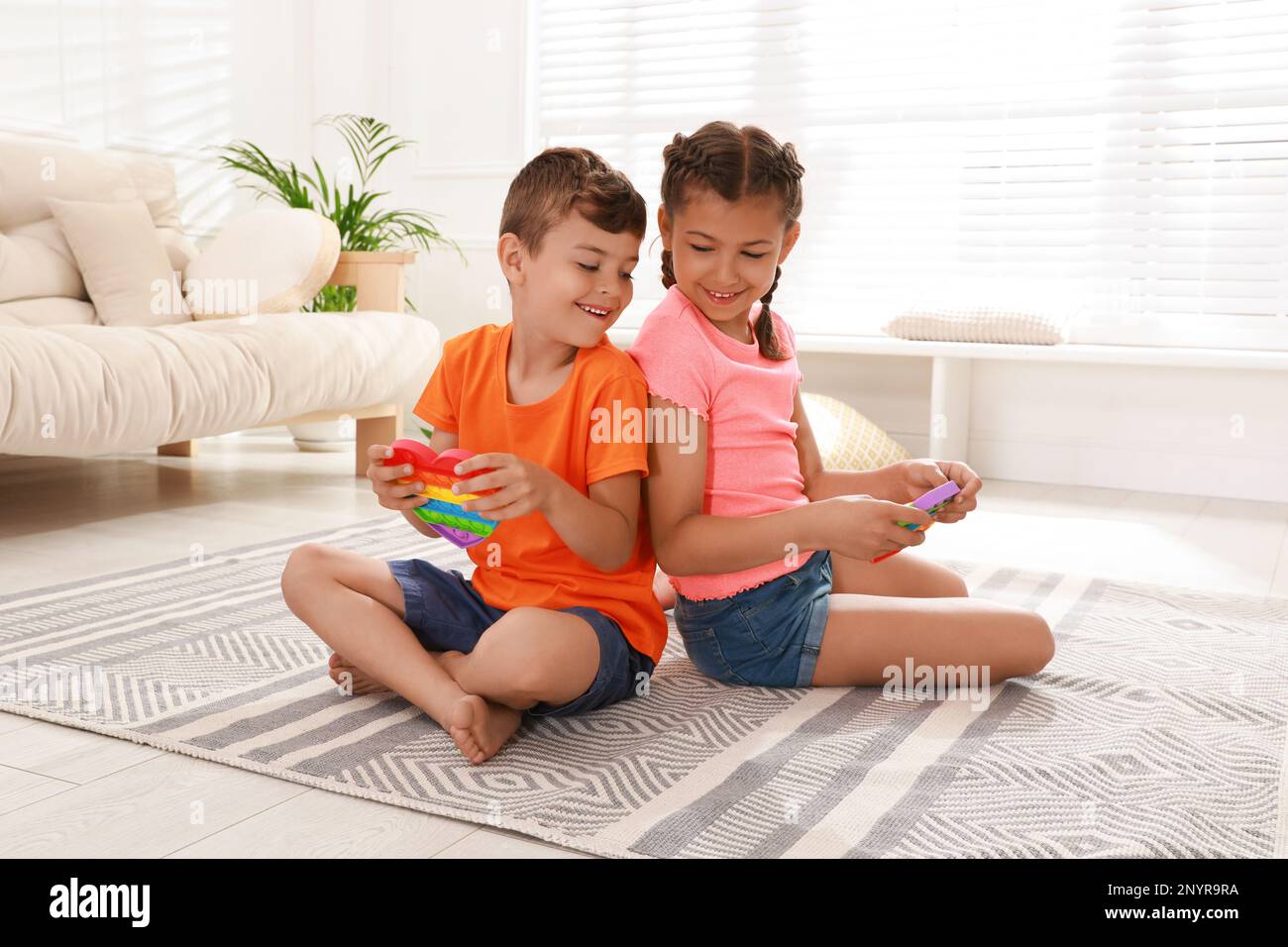 Children playing with pop it fidget toys on floor at home Stock Photo ...