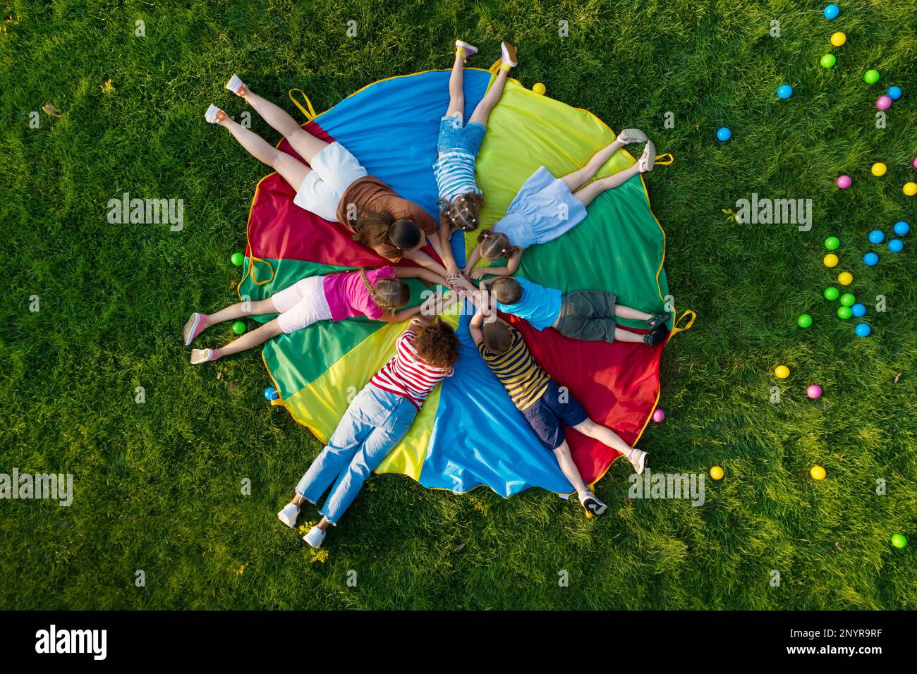 Group of children with teachers holding hands together on rainbow ...