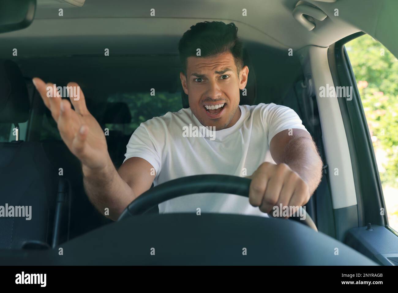 Stressed angry man in driver's seat of modern car, view through ...