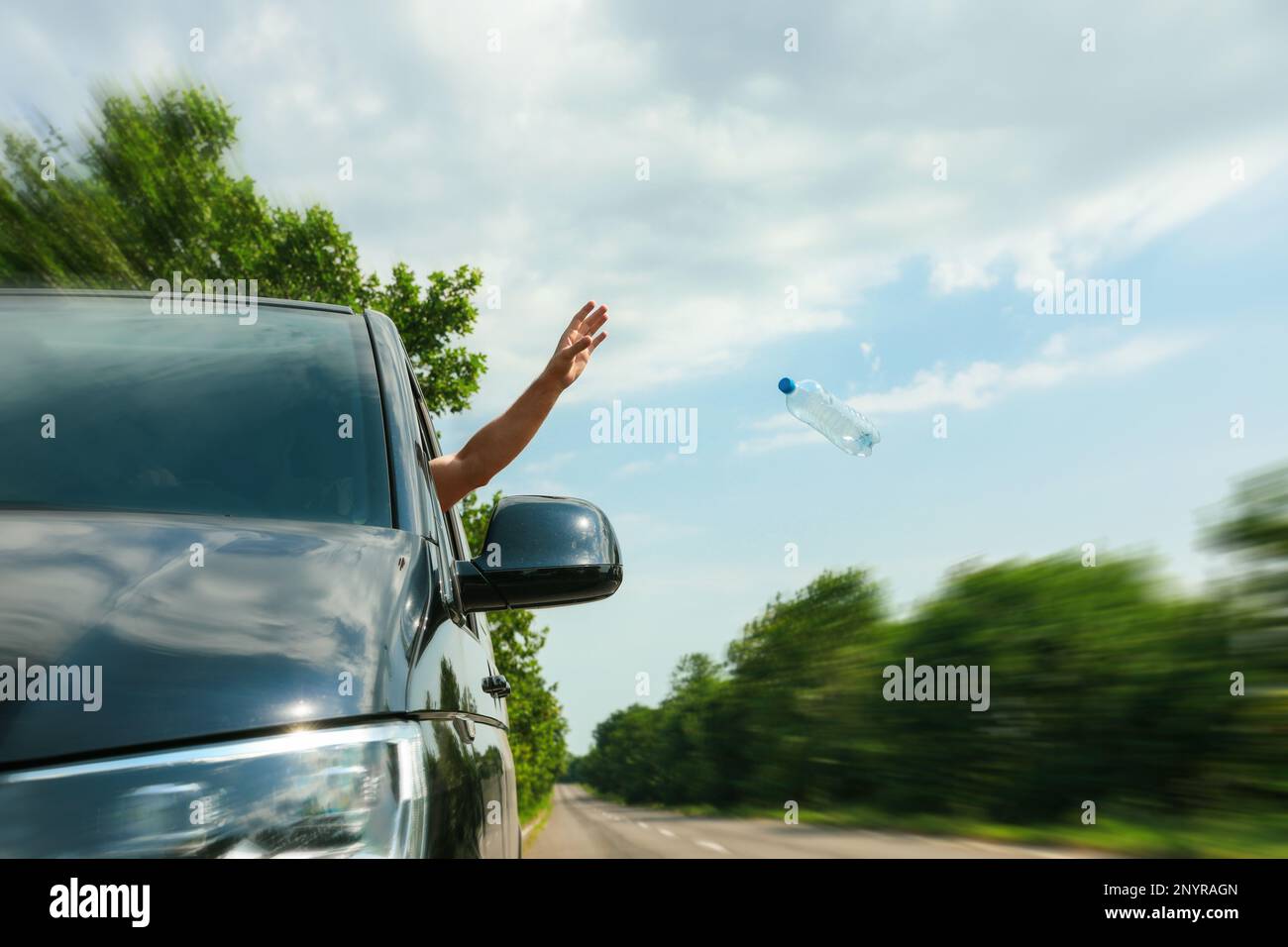 Driver throwing away plastic bottle from car window. Garbage on road ...