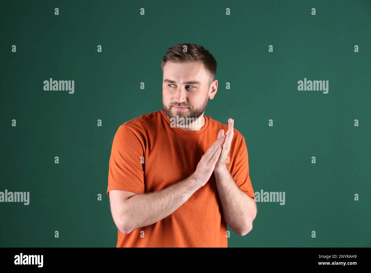 Greedy young man rubbing hands on green background Stock Photo - Alamy