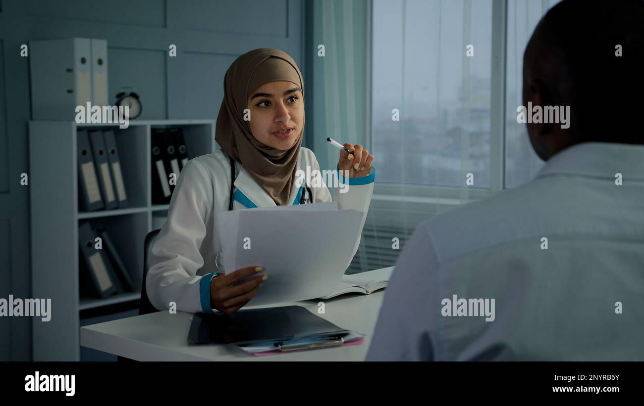 Caring young female practitioner medic showing paper health testing to ...